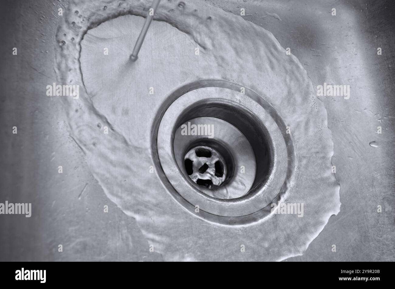 Water flowing from a kitchen or bathroom faucet into a stainless steel ...