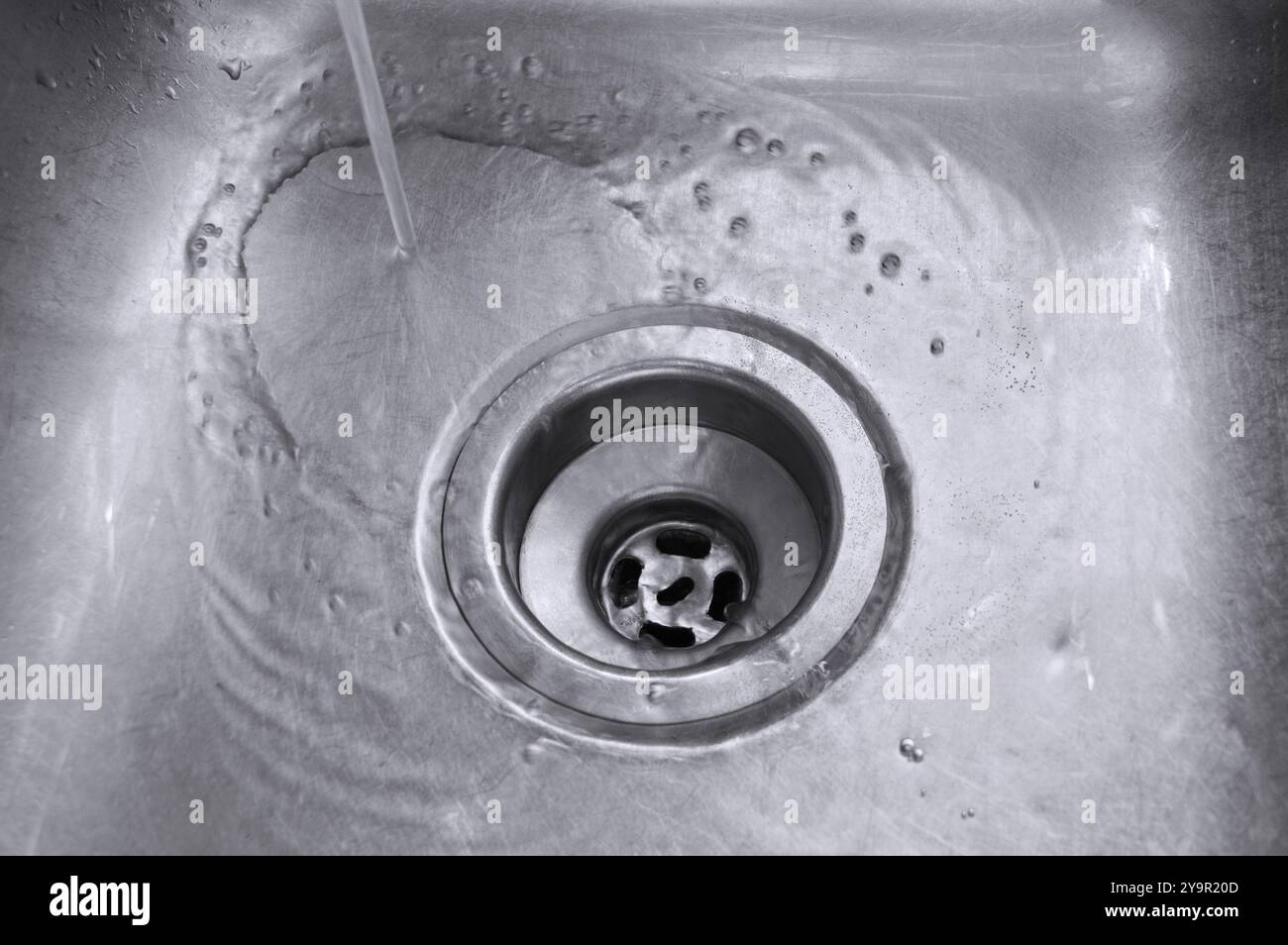 Water flowing from a kitchen or bathroom faucet into a stainless steel ...