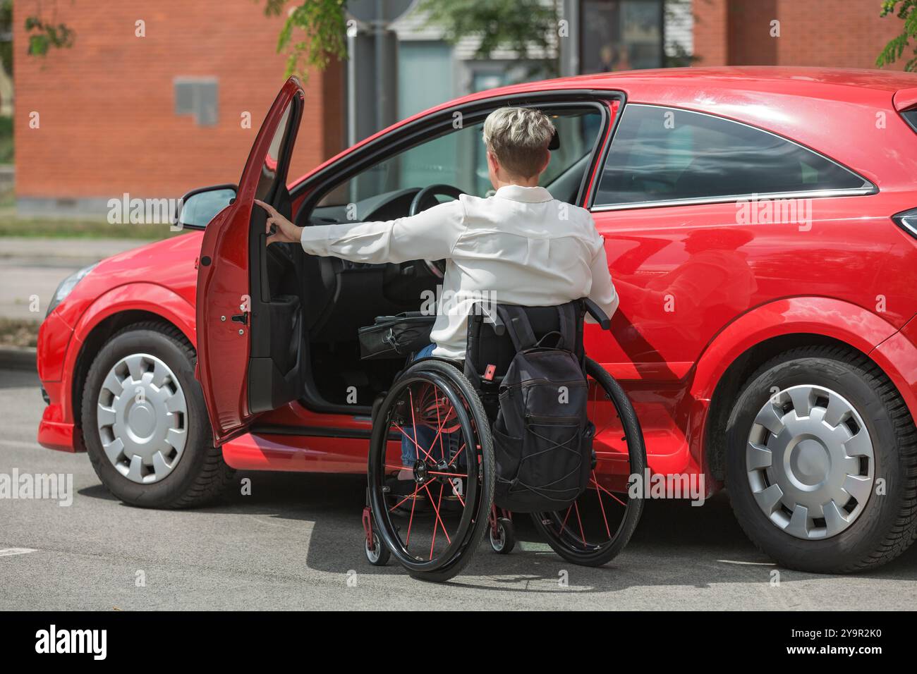Female driver with disability entering a car, a wheelchair user on the ...