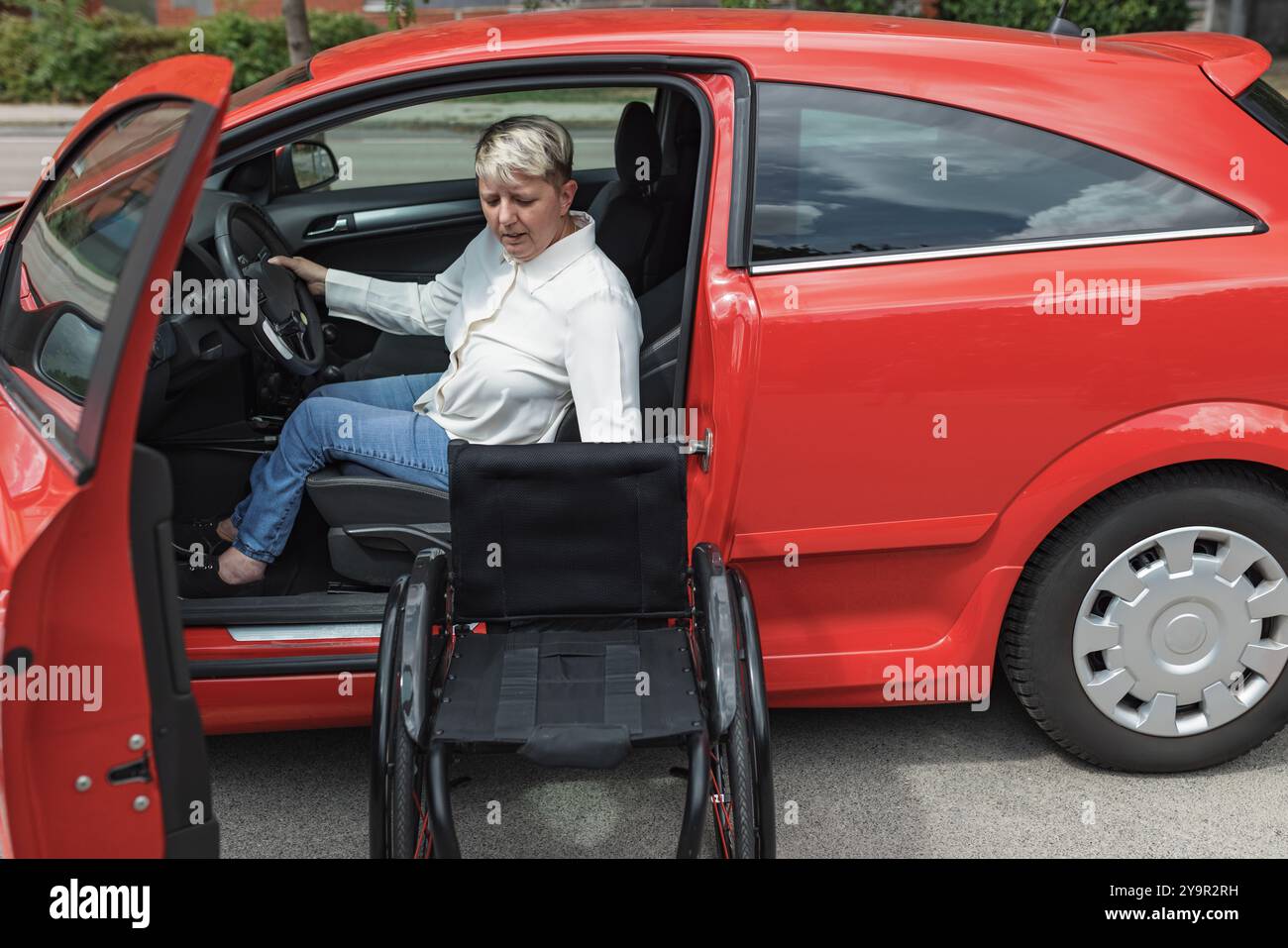 Female driver with disability entering a car, a wheelchair user on the ...