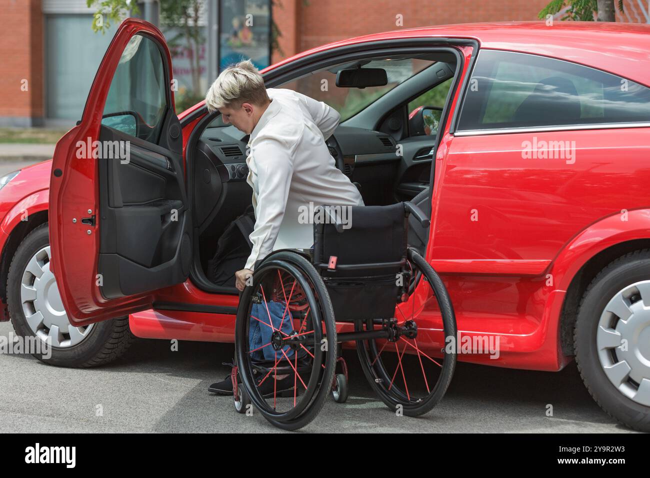 Female driver with disability entering a car, a wheelchair user on the ...