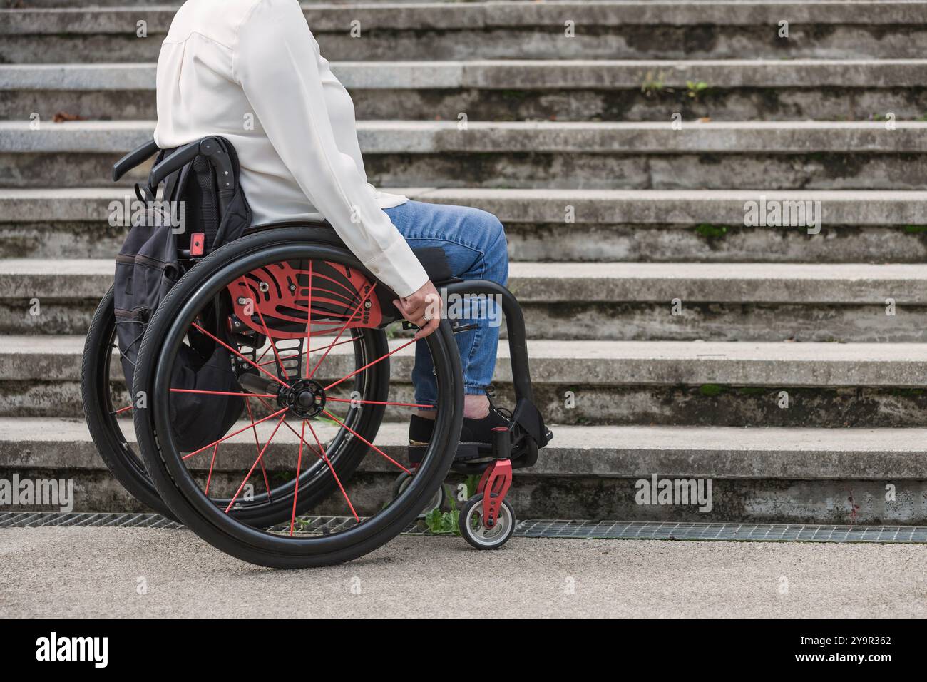 Woman in a wheelchair stopping and waiting at the bottom of inacessible ...