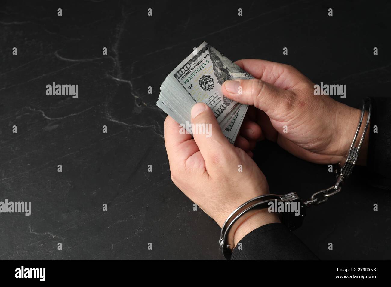 Corruption. Man in handcuffs holding dollar banknotes at grey textured ...