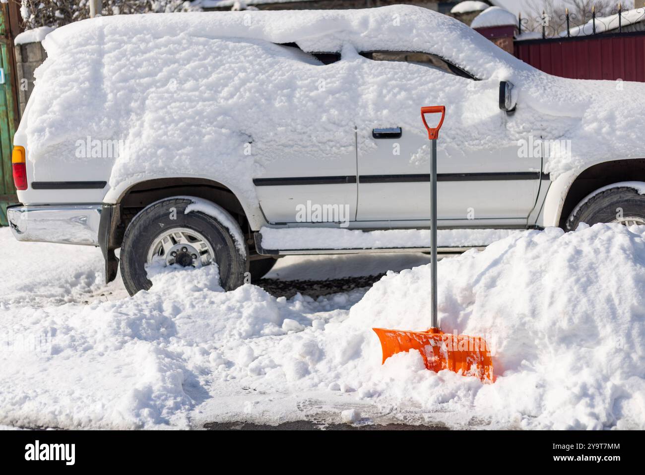 orange snow shovel sticking out from snowdrift in front of snow covered ...