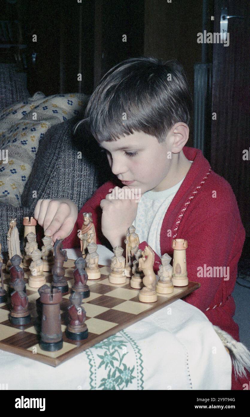 1970s, young boy in his dressing gown playing a game of chess, working ...