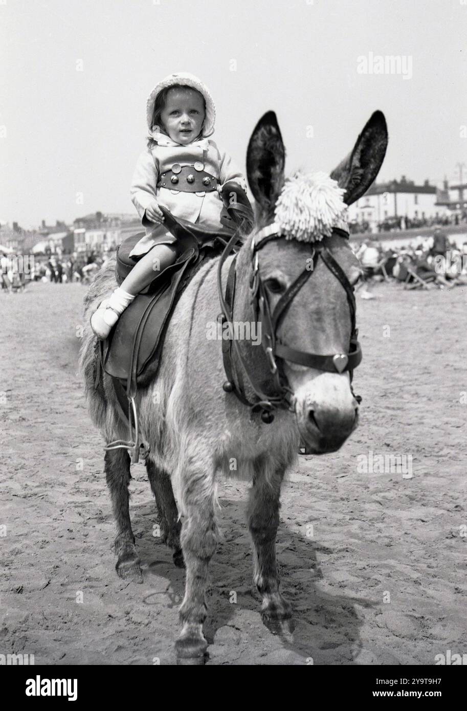 1950s, historical, seaside donkey ride, a little girl sitting on a ...