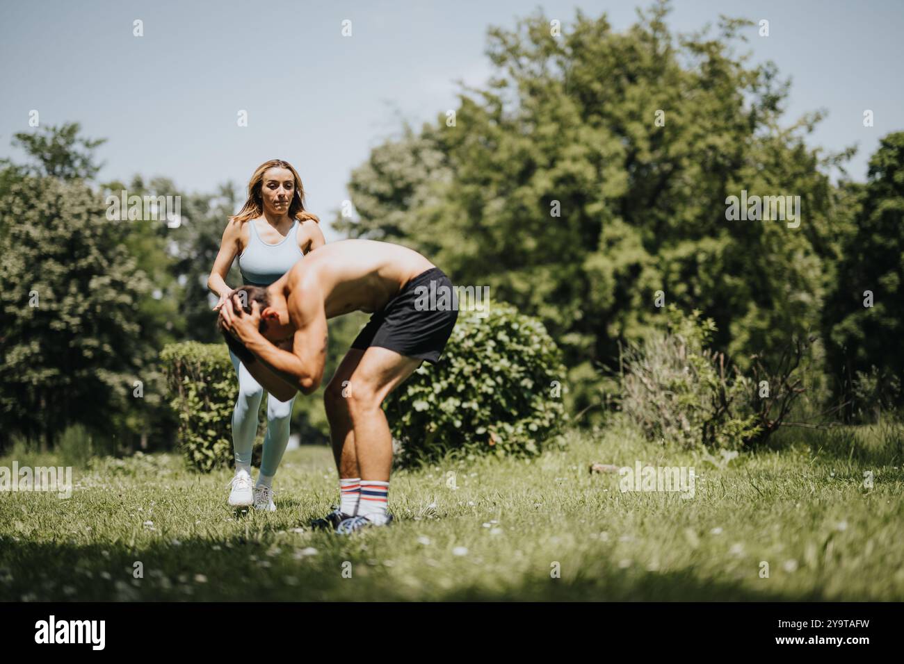 Athletic man jumping over his female friend during an outdoor workout ...