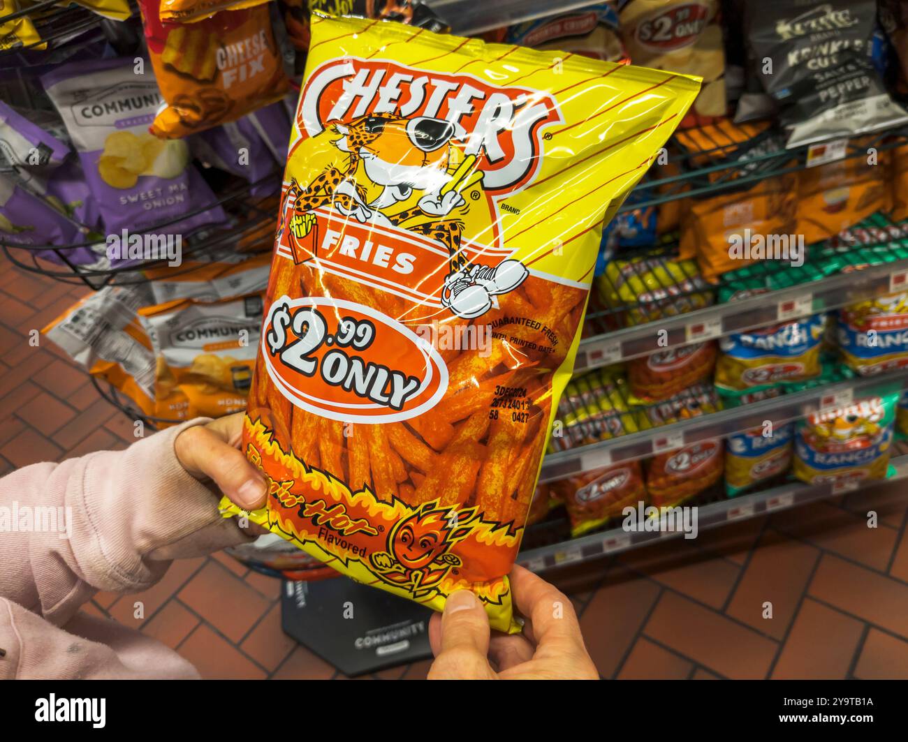 A shopper chooses a package of Chester’s Flamin’ Hot Fries, priced at ...