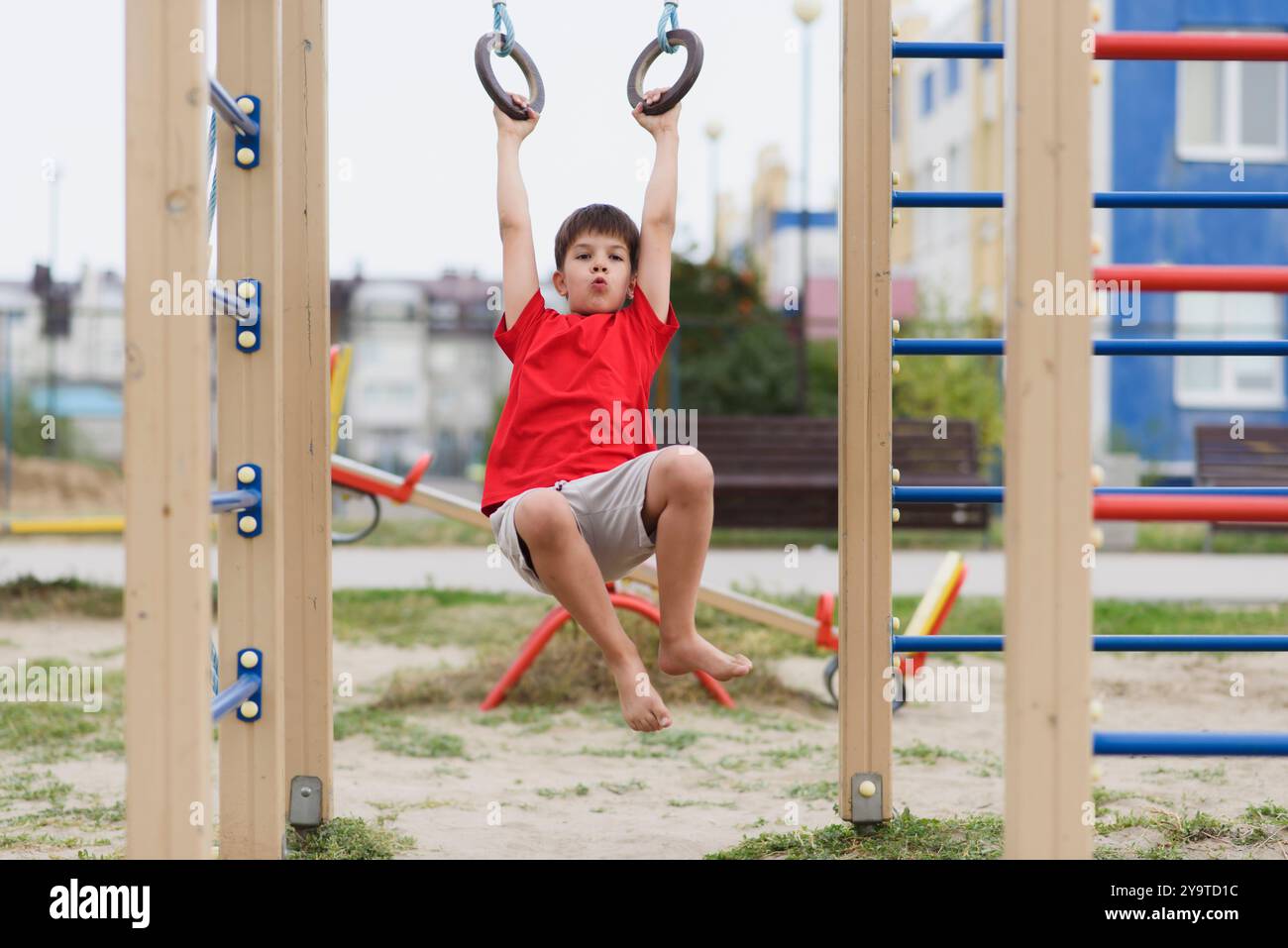 Happy boy playing and hanging on rings on playground. Kids exercises ...