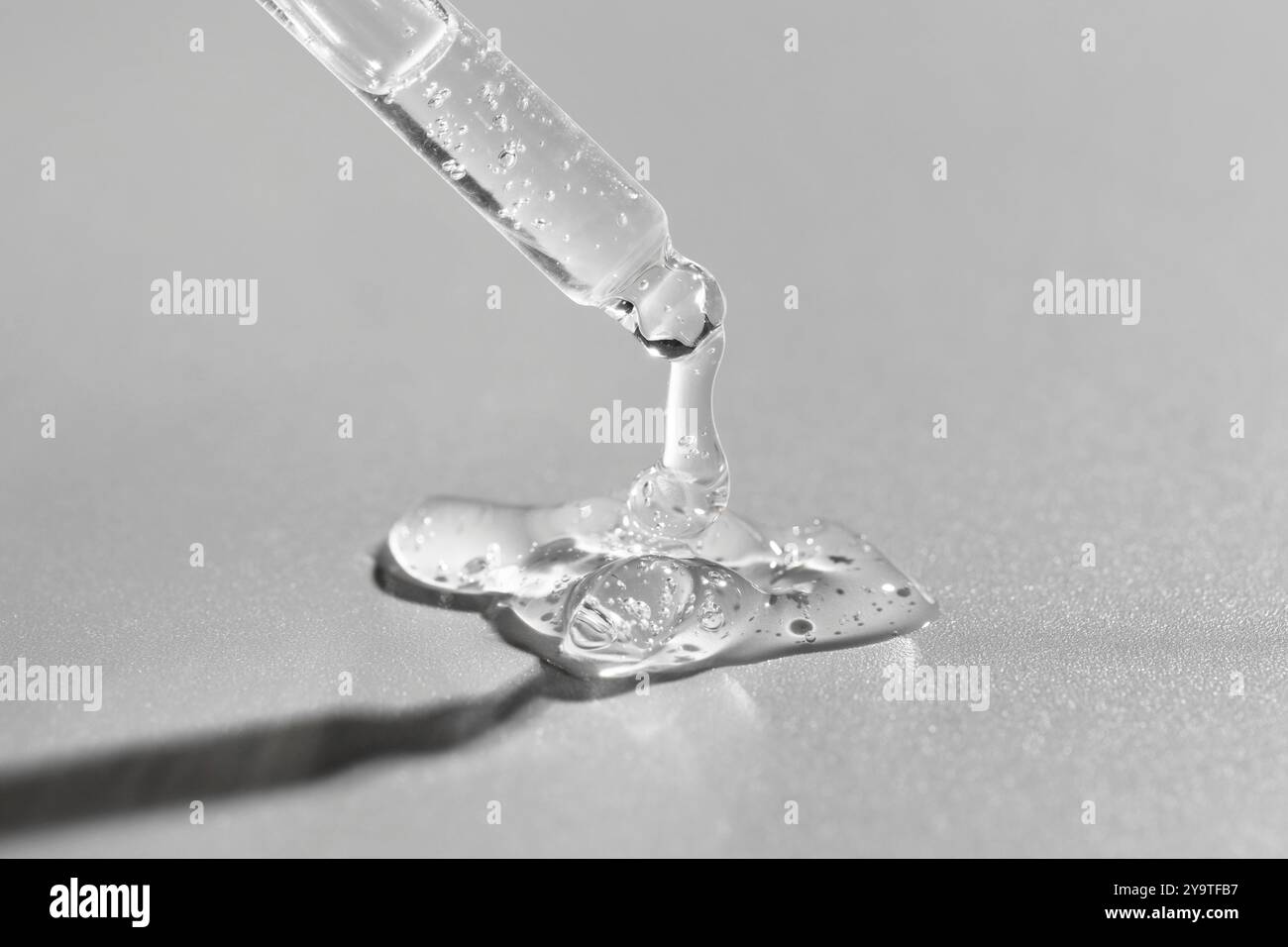 Dripping cosmetic serum from pipette on grey background, closeup Stock ...