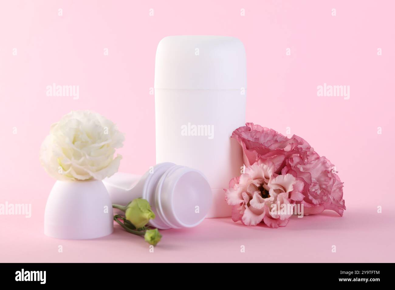 Different deodorants and beautiful eustoma flowers on pink background ...