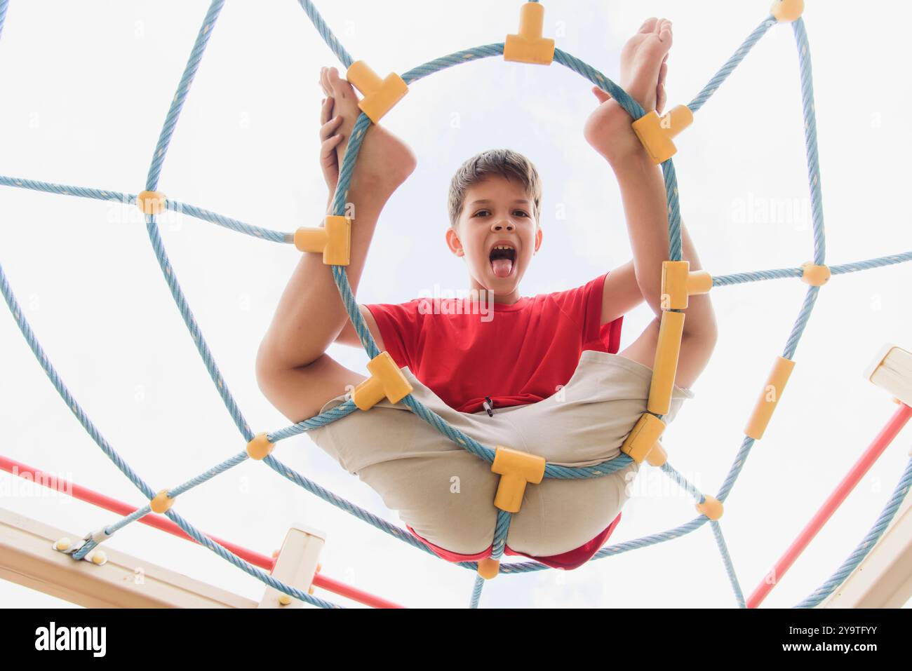 Happy boy playing and hanging on ropes on playground. Children's ...