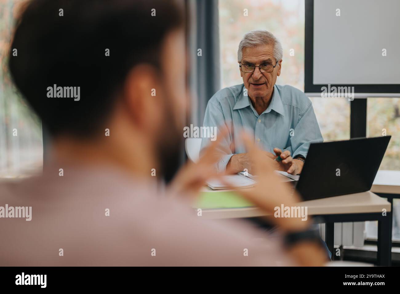 Elderly professor engaging with students in classroom discussion Stock ...