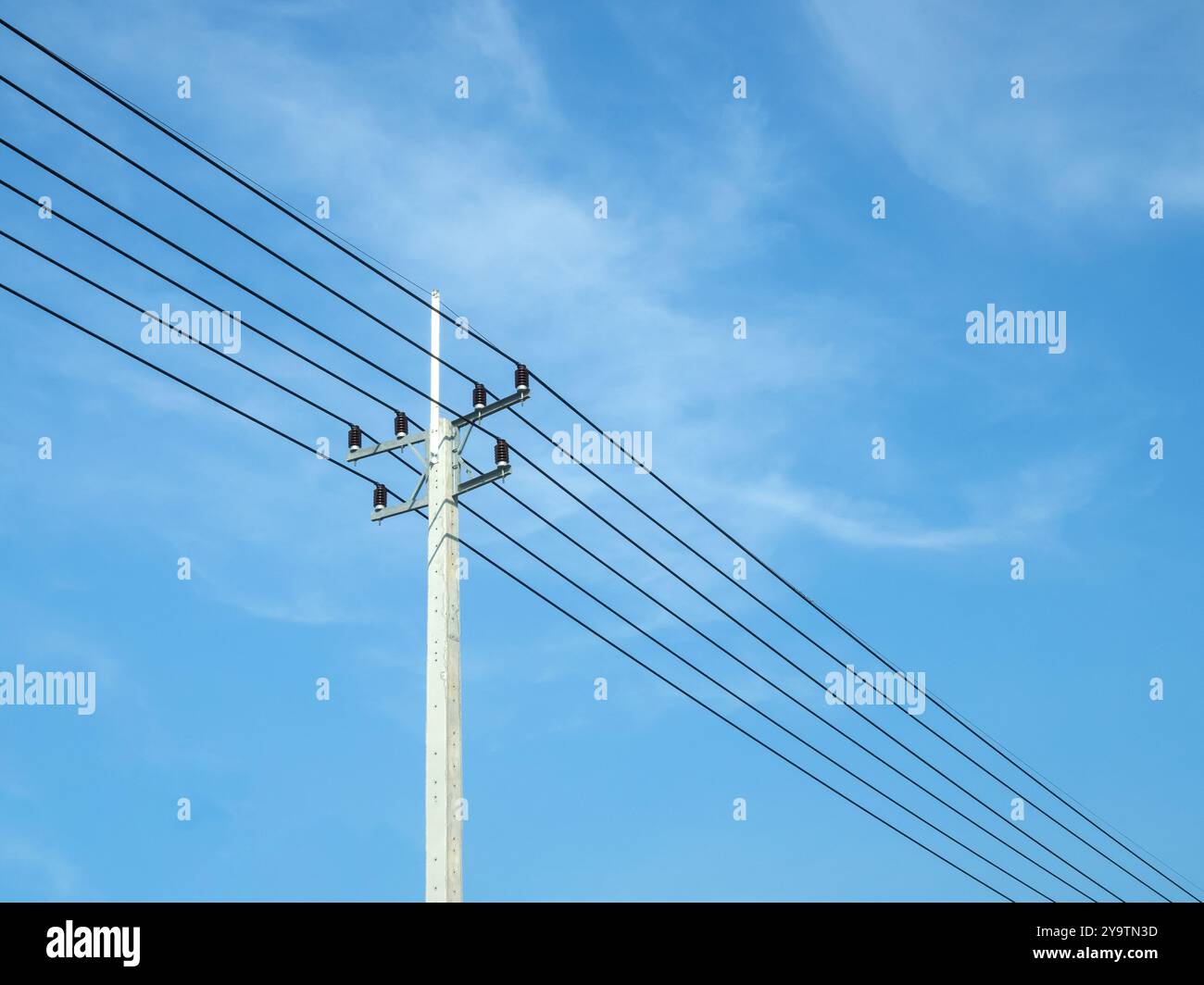 Reinforced concrete pillar with high-voltage wires against a clear blue ...