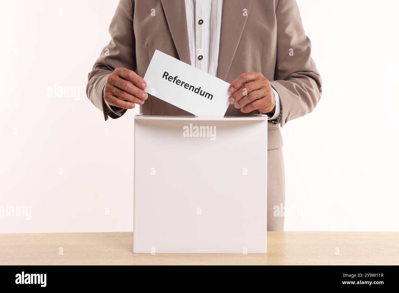 Referendum. Man putting his vote into ballot box at wooden table ...