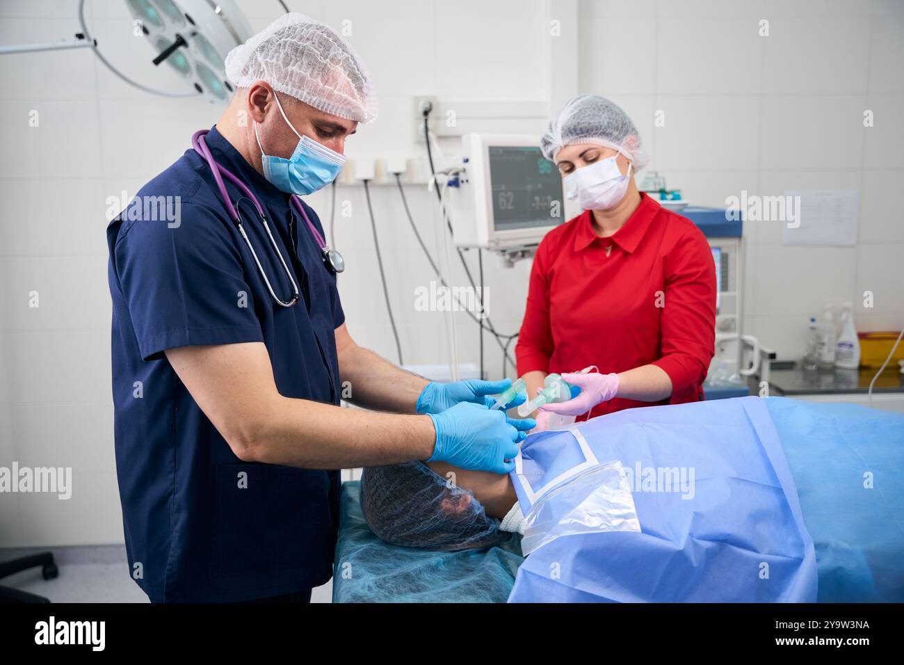 Male anesthesiologist working in operating room with female assistant ...