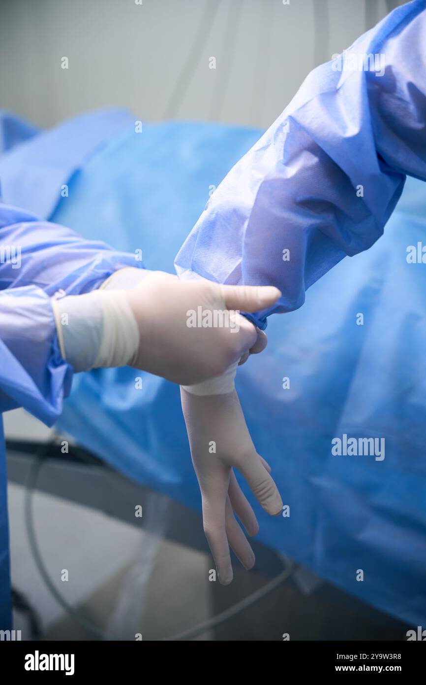 Medical staff help a doctor put on a surgical uniform Stock Photo - Alamy