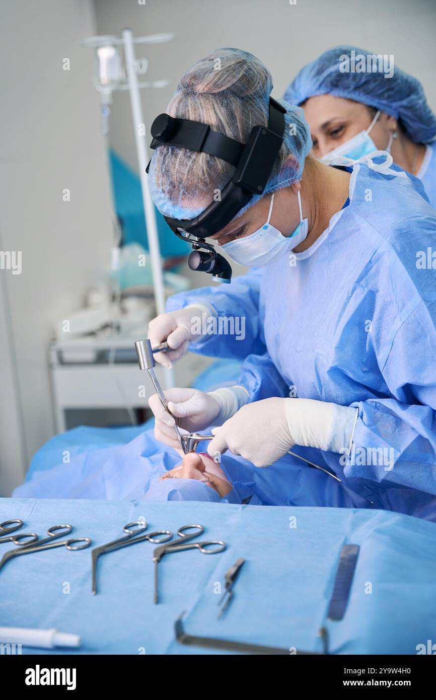 Surgical nurse assisting surgeon during ethmoidectomy operation ...