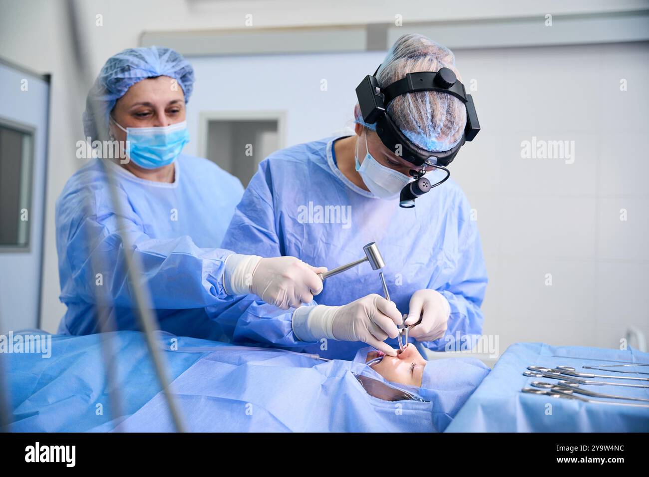 Experienced clinic employee assists a surgeon as a patient undergoes a ...