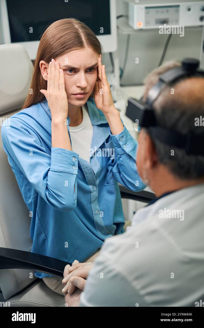 Male patient touches her temples during consultation Stock Photo - Alamy