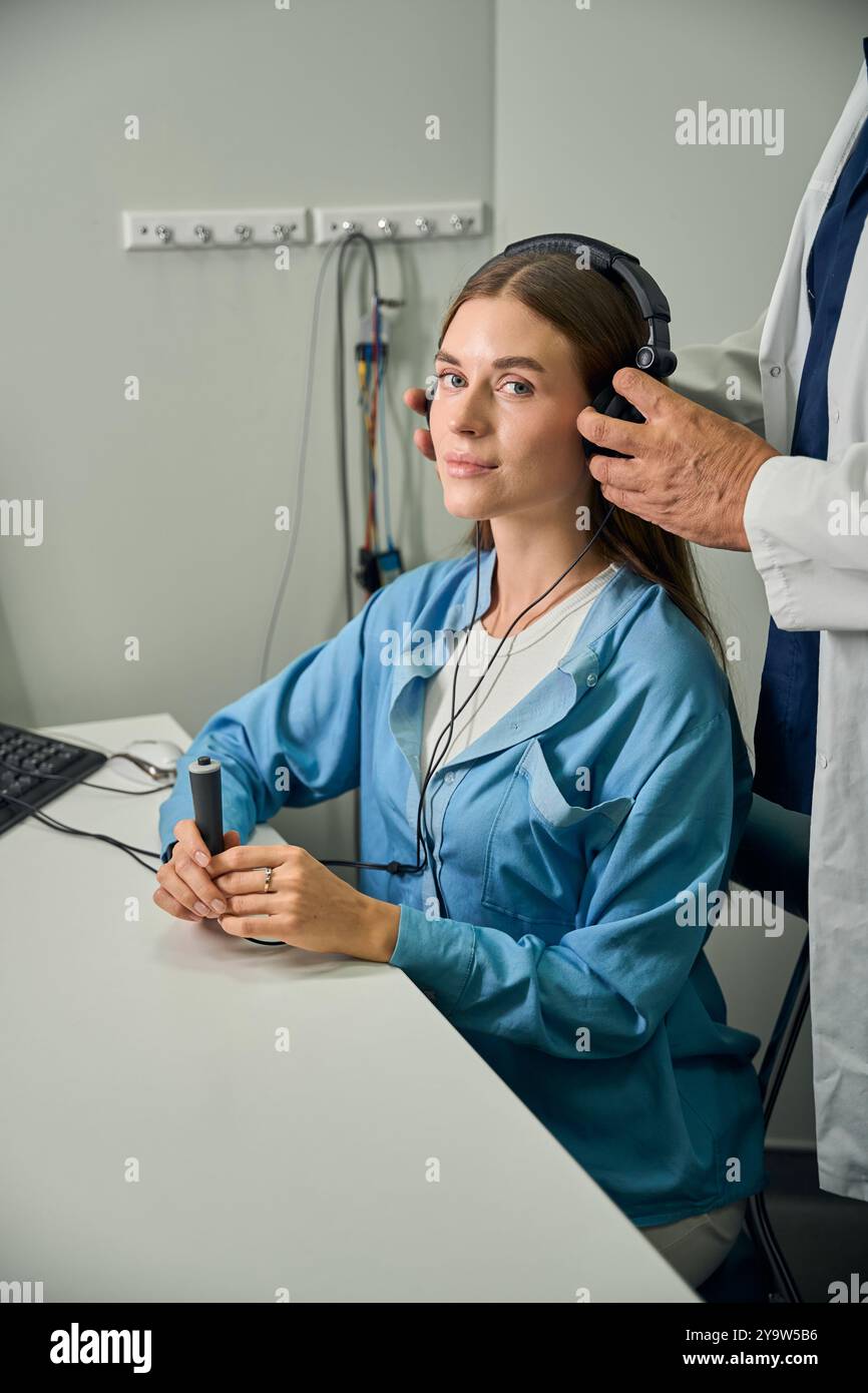 Male doctor adjusts headphones on patients head Stock Photo - Alamy