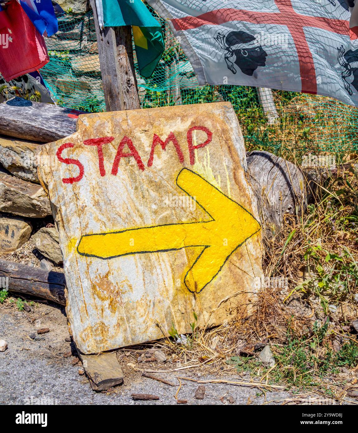 A weathered stone sign with a yellow arrow and the word “STAMP ...