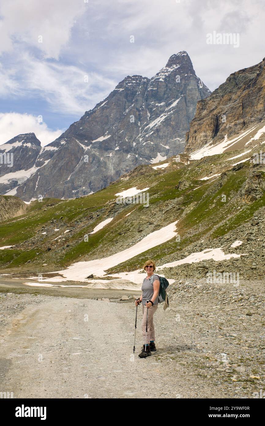 a female hiker with backpack and hiking poles stops to admire the ...