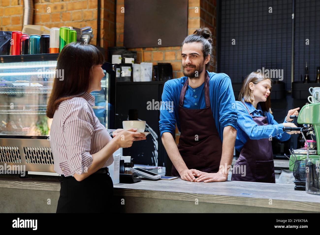 Guy working in cafe with cup of coffee at bar counter serving female ...
