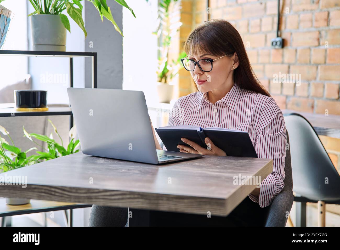 Middle-aged business woman working remotely with laptop in coworking ...