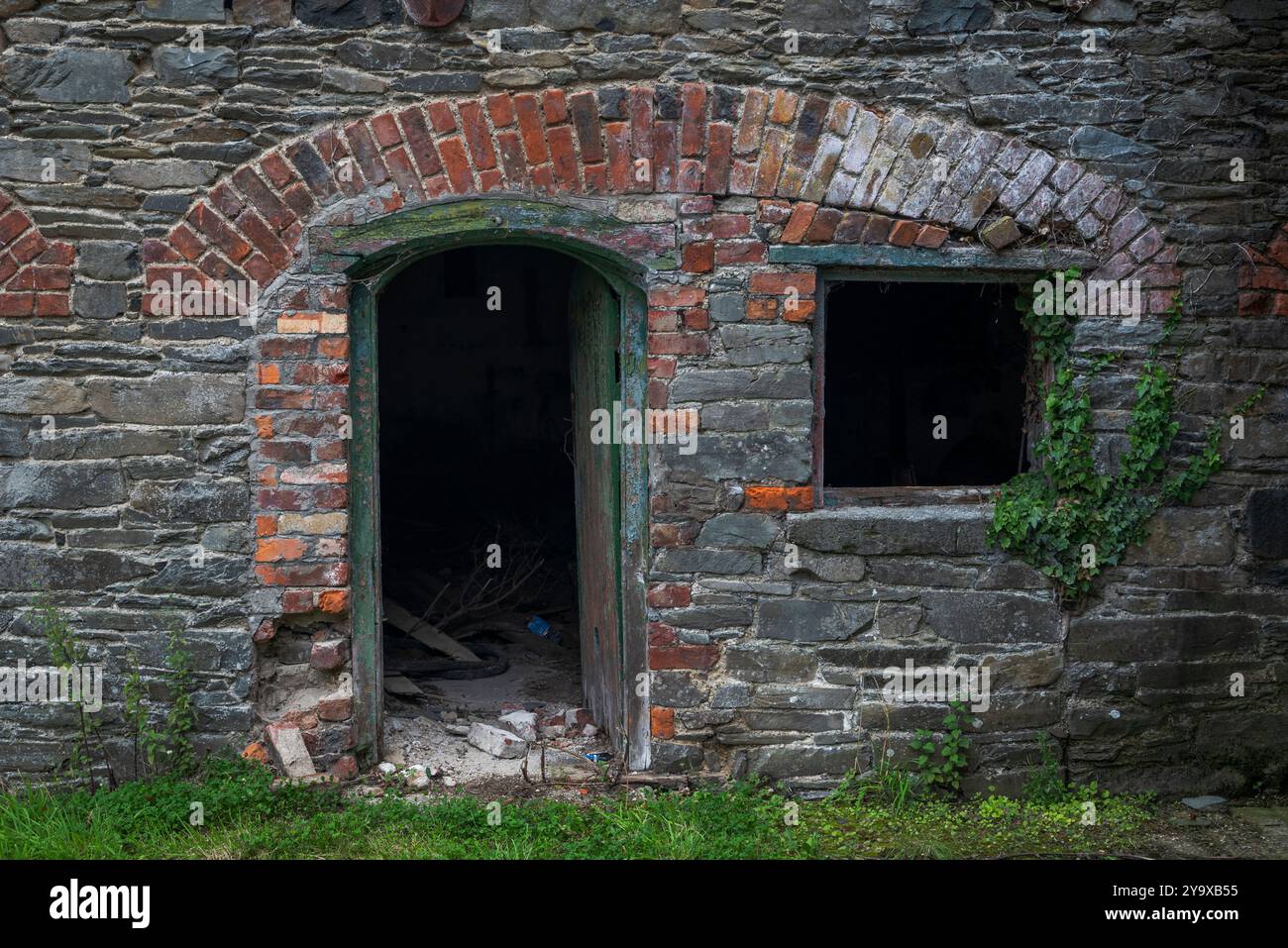 The wall of an abandoned, industrial building shows crumbling stone and ...