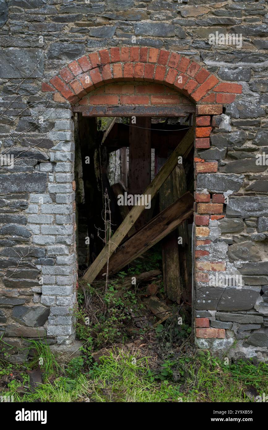 Detail of a wooden door slightly ajar in a stone wall with brick ...