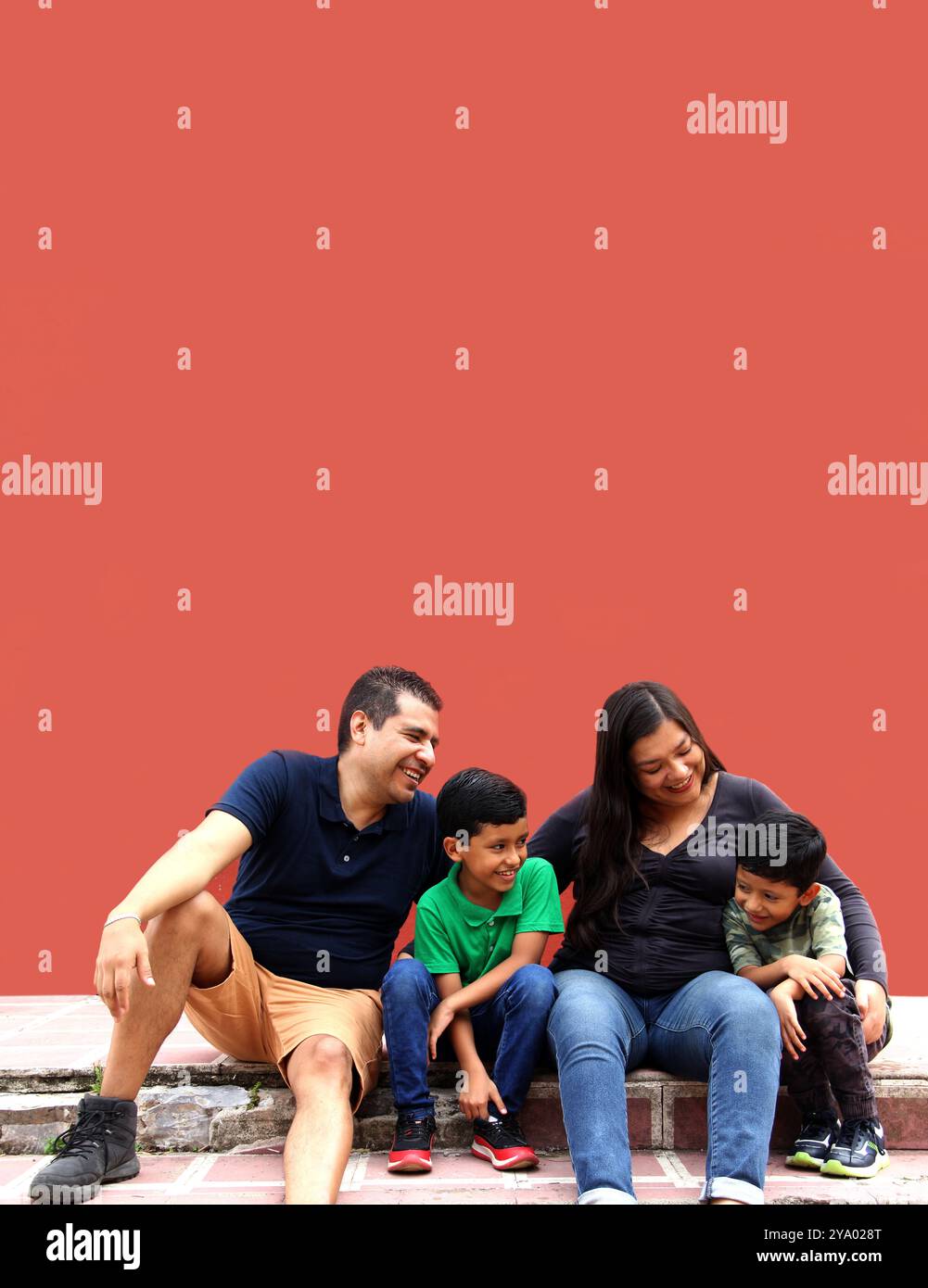 Latin, Hispanic family of mom, dad and children are sitting in the park ...