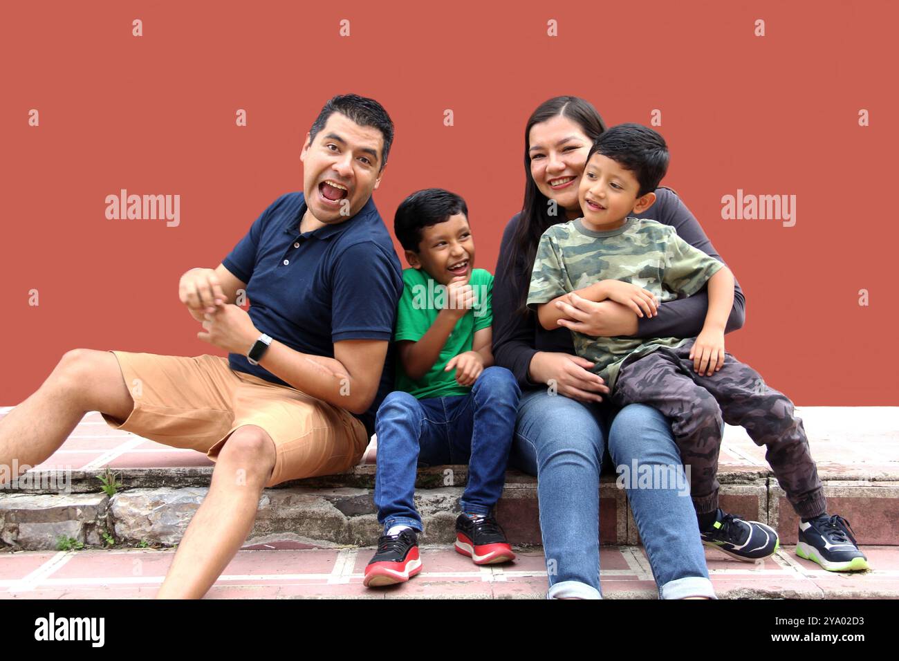 Latin, Hispanic family of mom, dad and children are sitting in the park ...