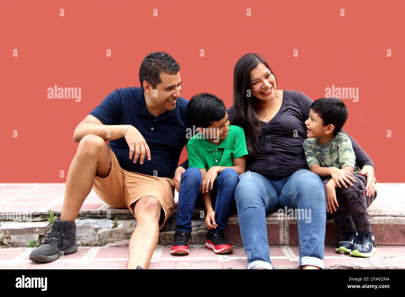 Latin, Hispanic family of mom, dad and children are sitting in the park ...