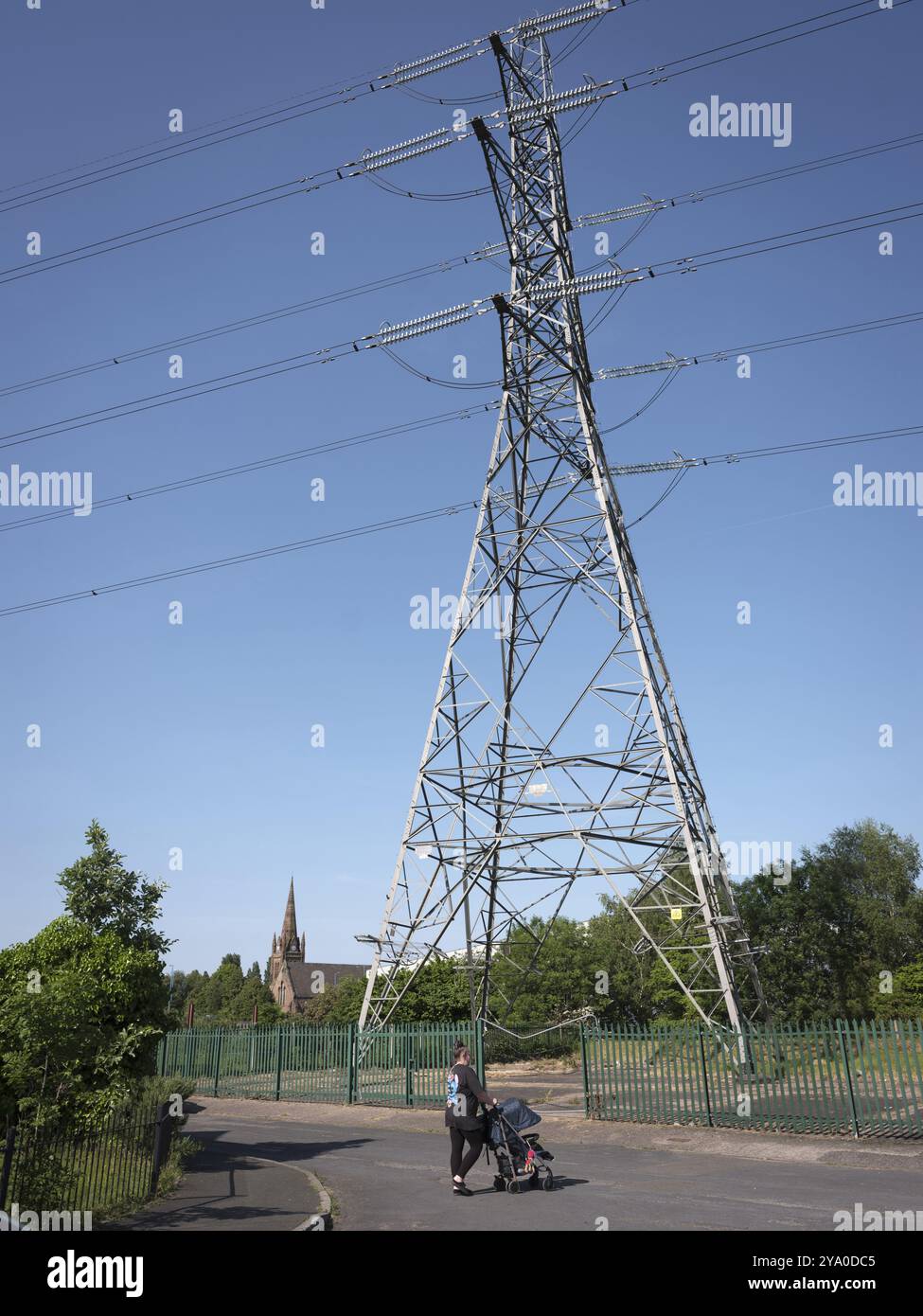 Woman with child in buggy passing beneath high voltage power lines ...