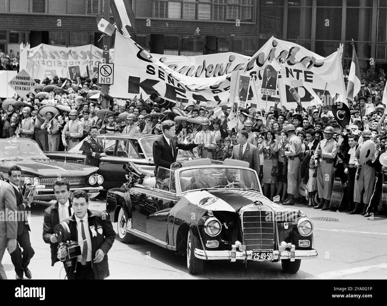 U.S. President John F. Kennedy waving to crowd from convertible car ...