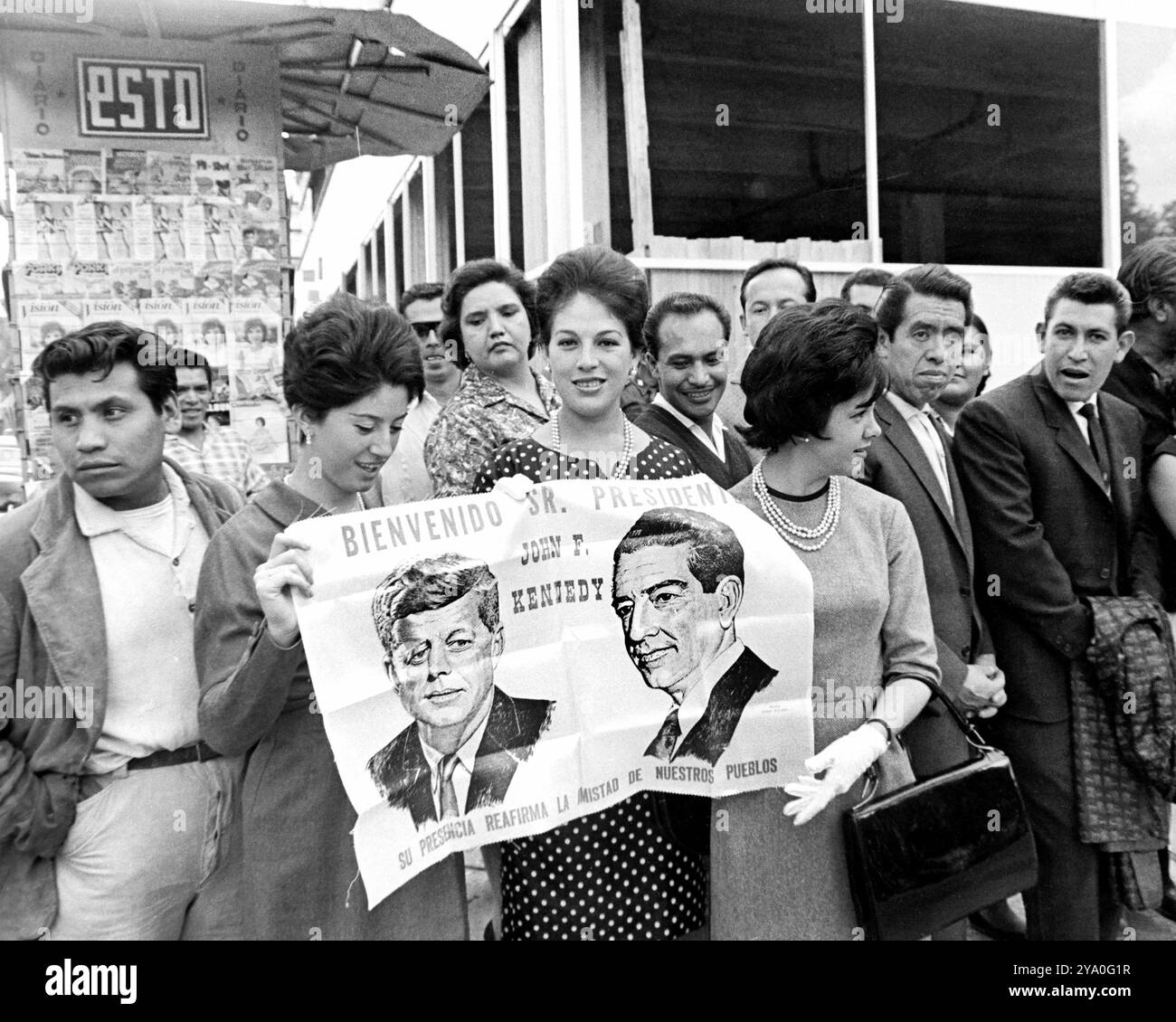 Spectators holding sign to greet U.S. President John F. Kennedy during ...