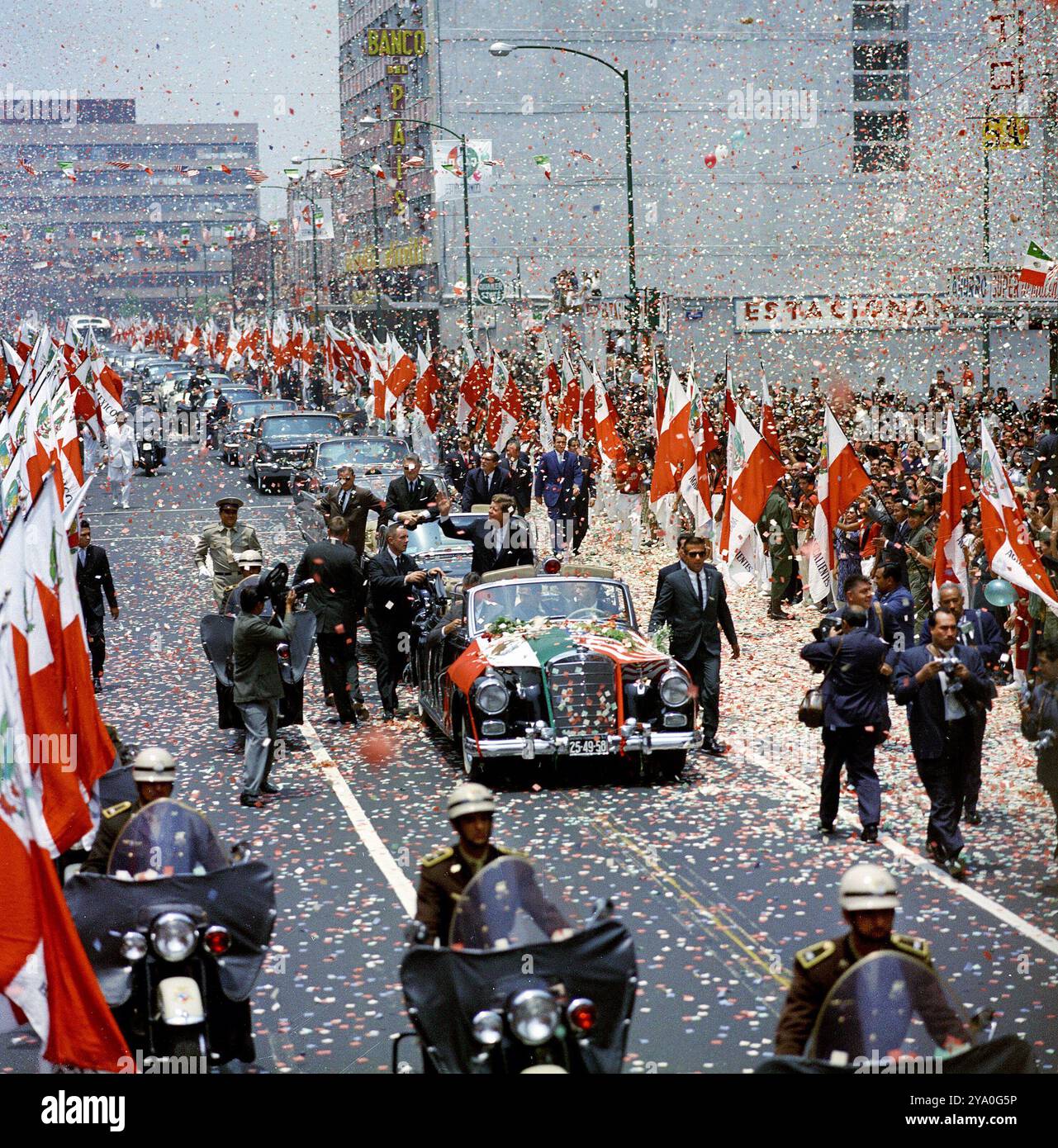 U.S. President John F. Kennedy waving to crowd from convertible car as ...