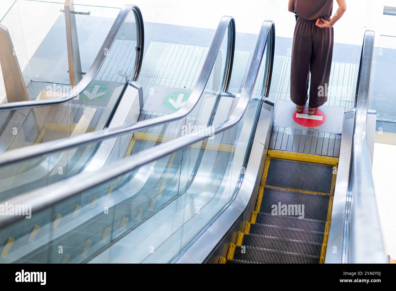 A person standing on an escalator, facing downwards. The escalator has ...