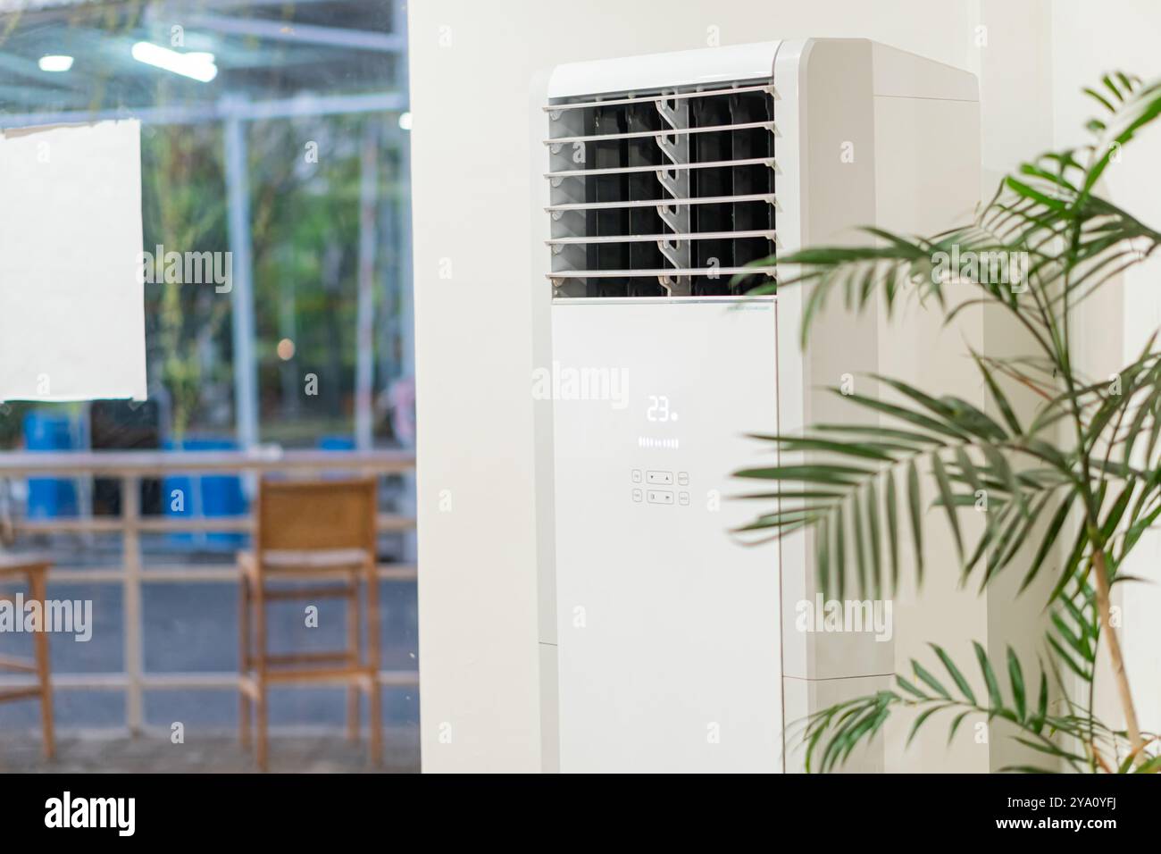 A modern air conditioning unit placed against a white wall in a bright ...