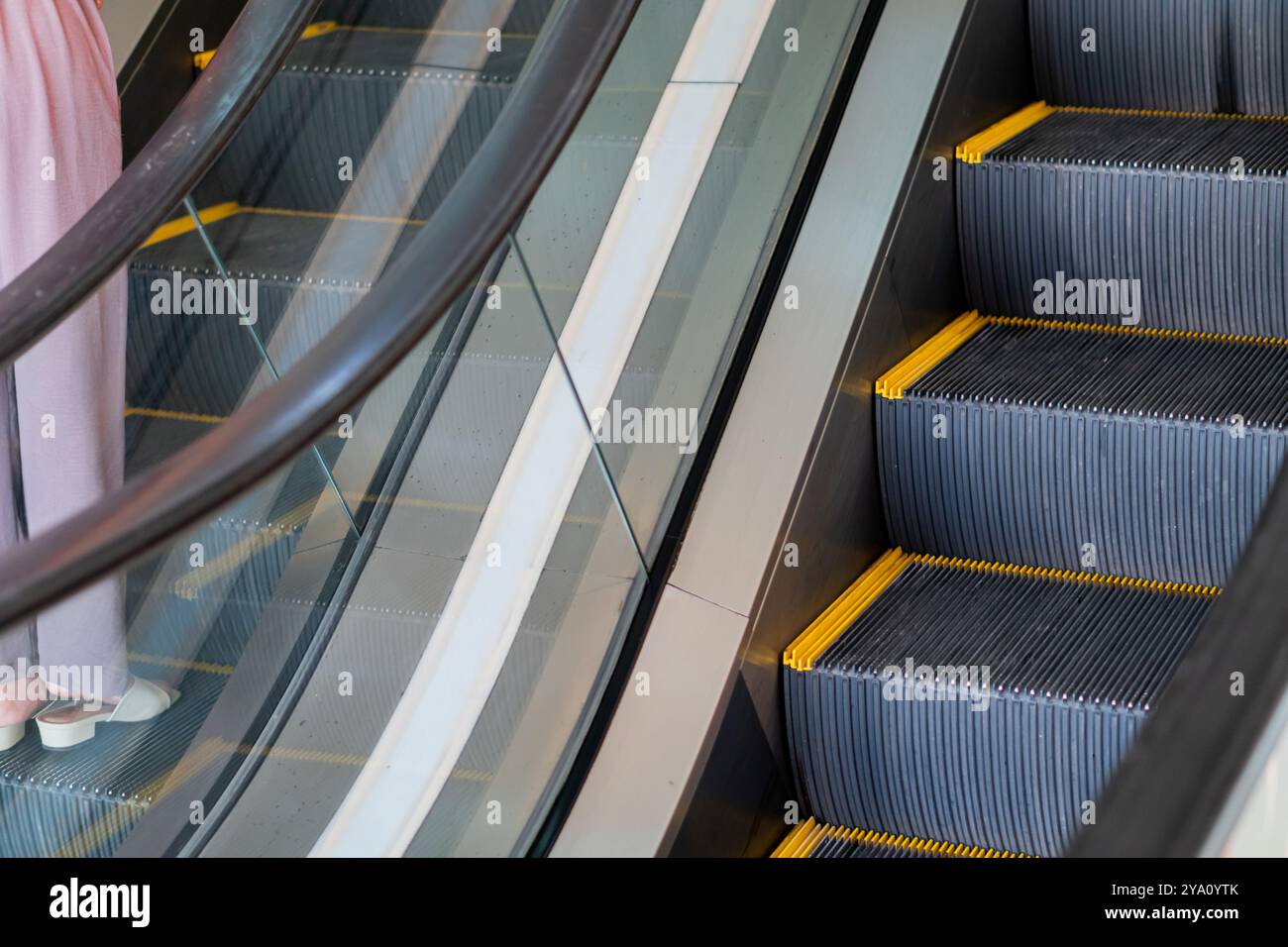 A close-up view of an escalator with a focus on the steps and handrail ...