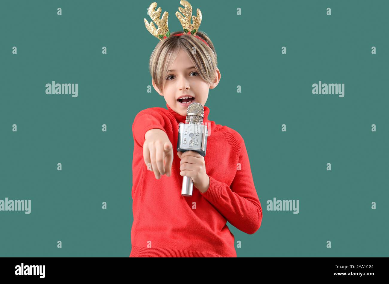 Cute little boy in Christmas deer horns with microphone singing on ...