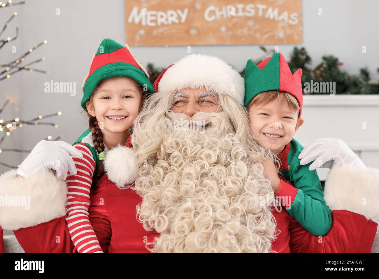 Little elves hugging Santa Claus at home on Christmas eve Stock Photo ...