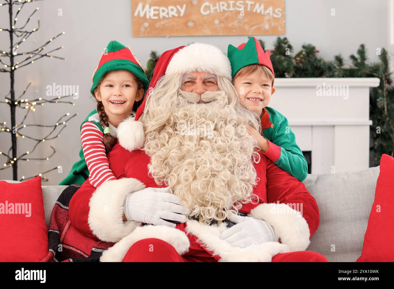 Little elves hugging Santa Claus at home on Christmas eve Stock Photo ...