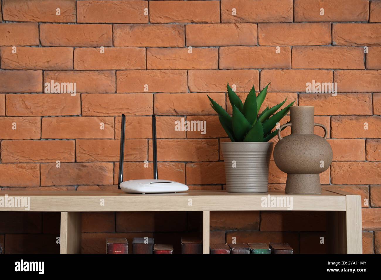 Modern wi-fi router with aloe and vase on shelf near brick wall Stock ...