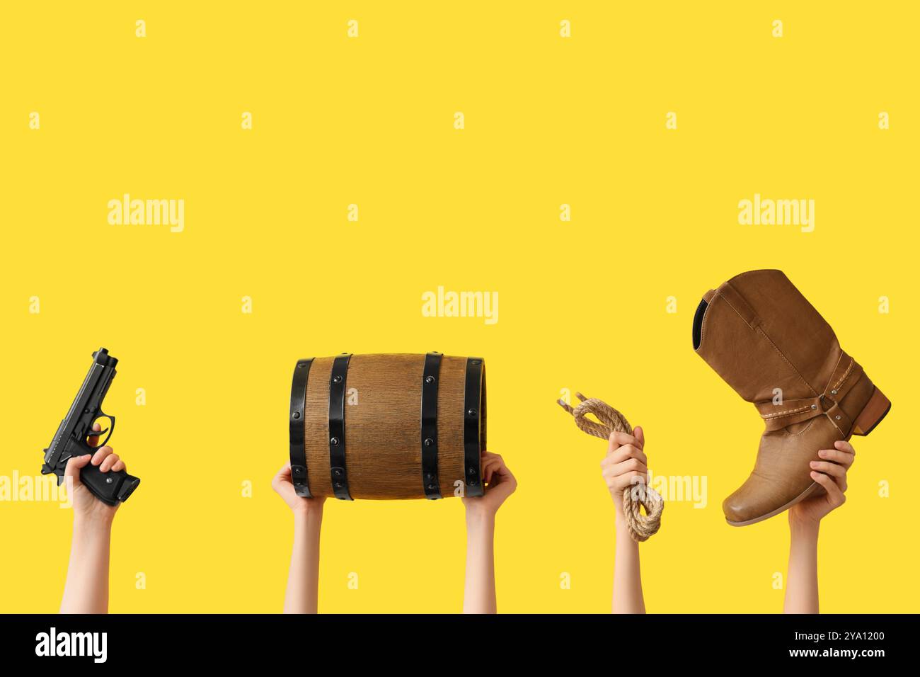 Female hands with wooden barrel, gun, lasso and cowboy shoe on yellow ...