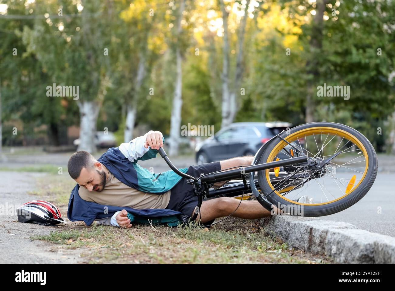 Young man fallen off his bike and lying on grass outdoors Stock Photo ...