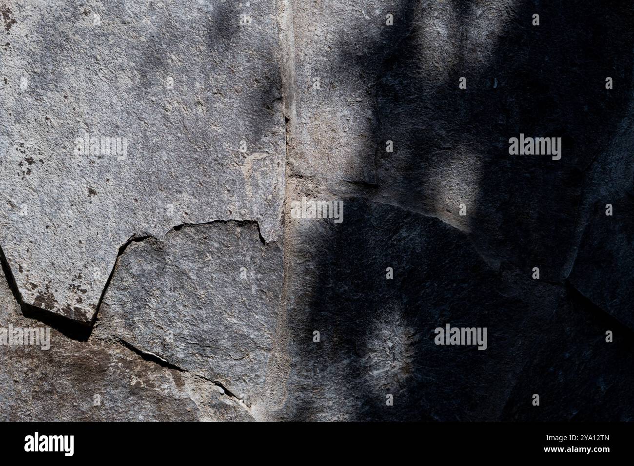 A close-up view of a textured stone wall with visible cracks and ...