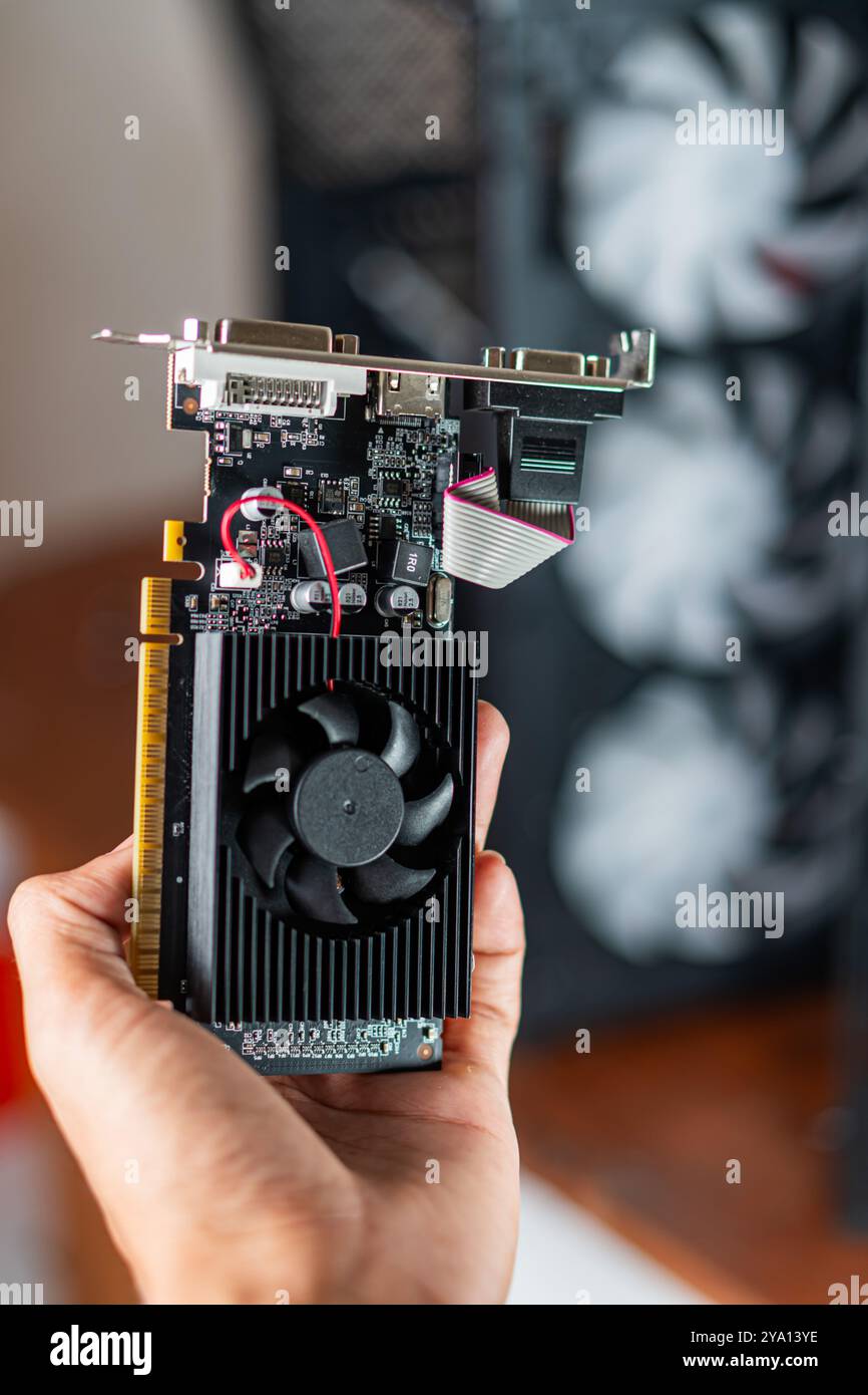 A person holding a graphics card with a black cooling fan and various ...