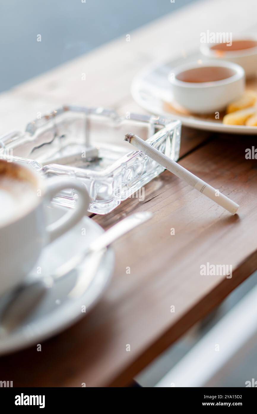 A cozy cafe scene featuring a cup of coffee, an ashtray with a ...